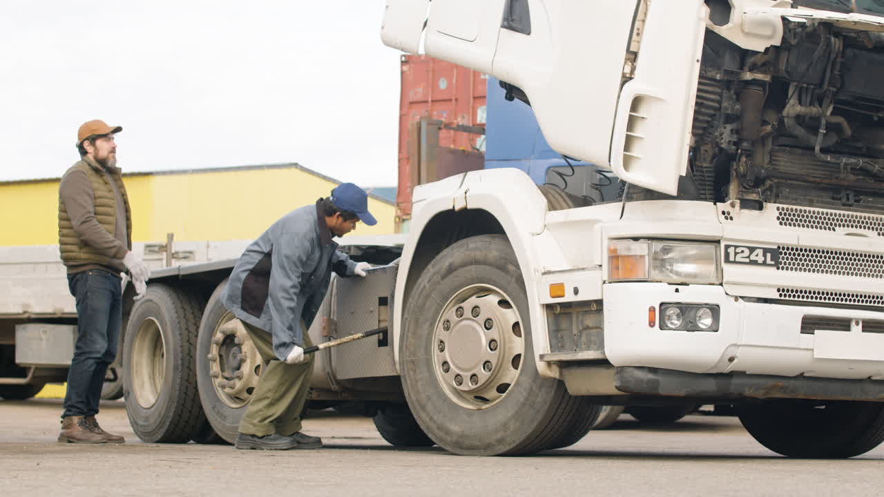 Premium stock video - Distant view of worker fixing a truck in a ...