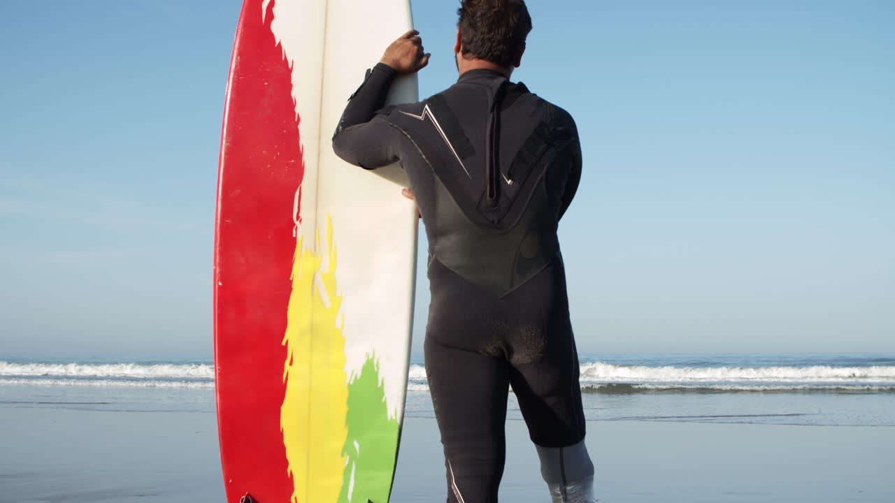 Premium stock video - Vertical shot of a male surfer in wetsuit with ...