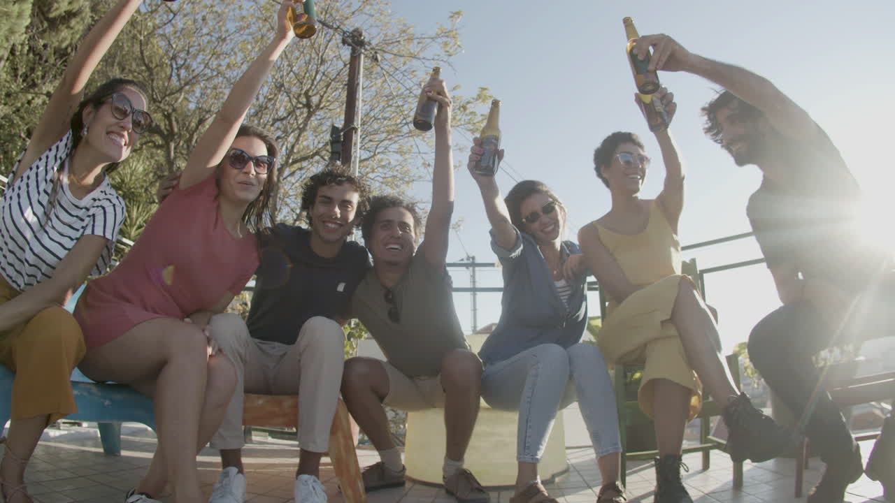 Free stock video - Happy friends raising bottles of beer up and looking ...