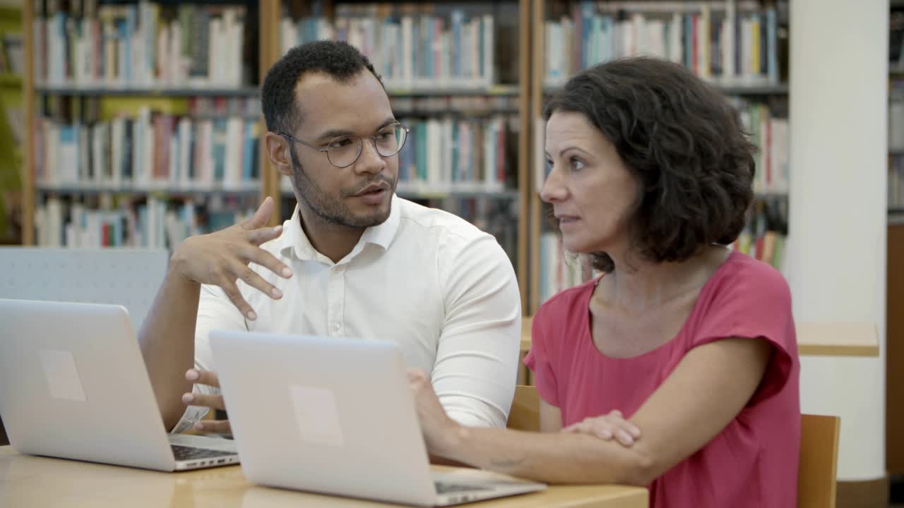 Free stock video - Slow motion shot of two people talking at library