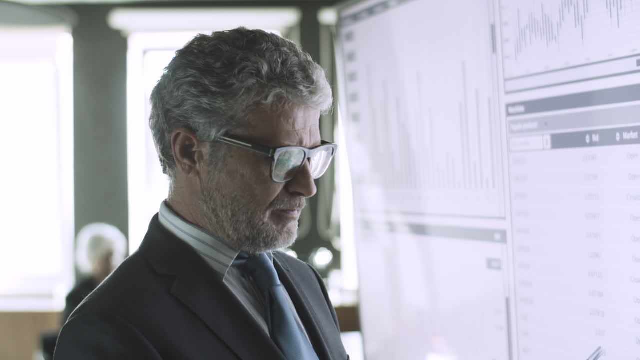 Free stock video - Experienced grey-haired ceo checking data on big screen