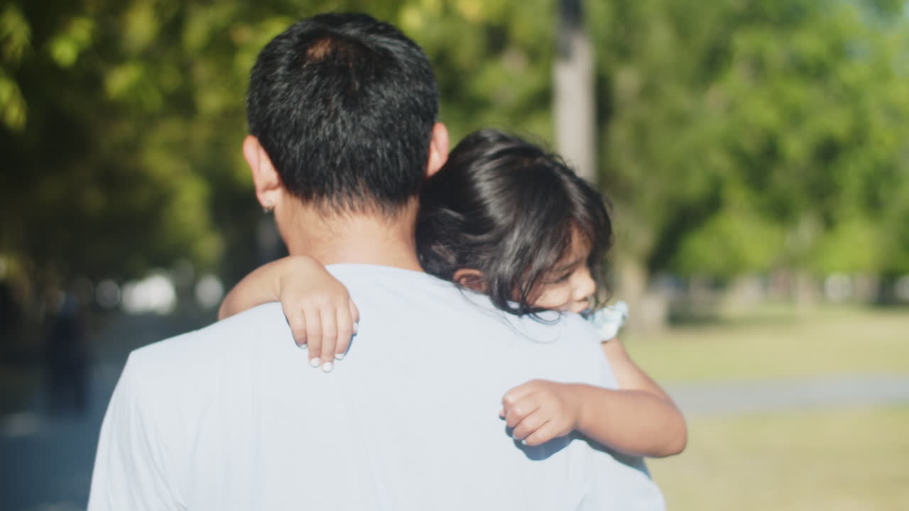 Free stock video - Rear view of asian father carrying his sleeping little daughter