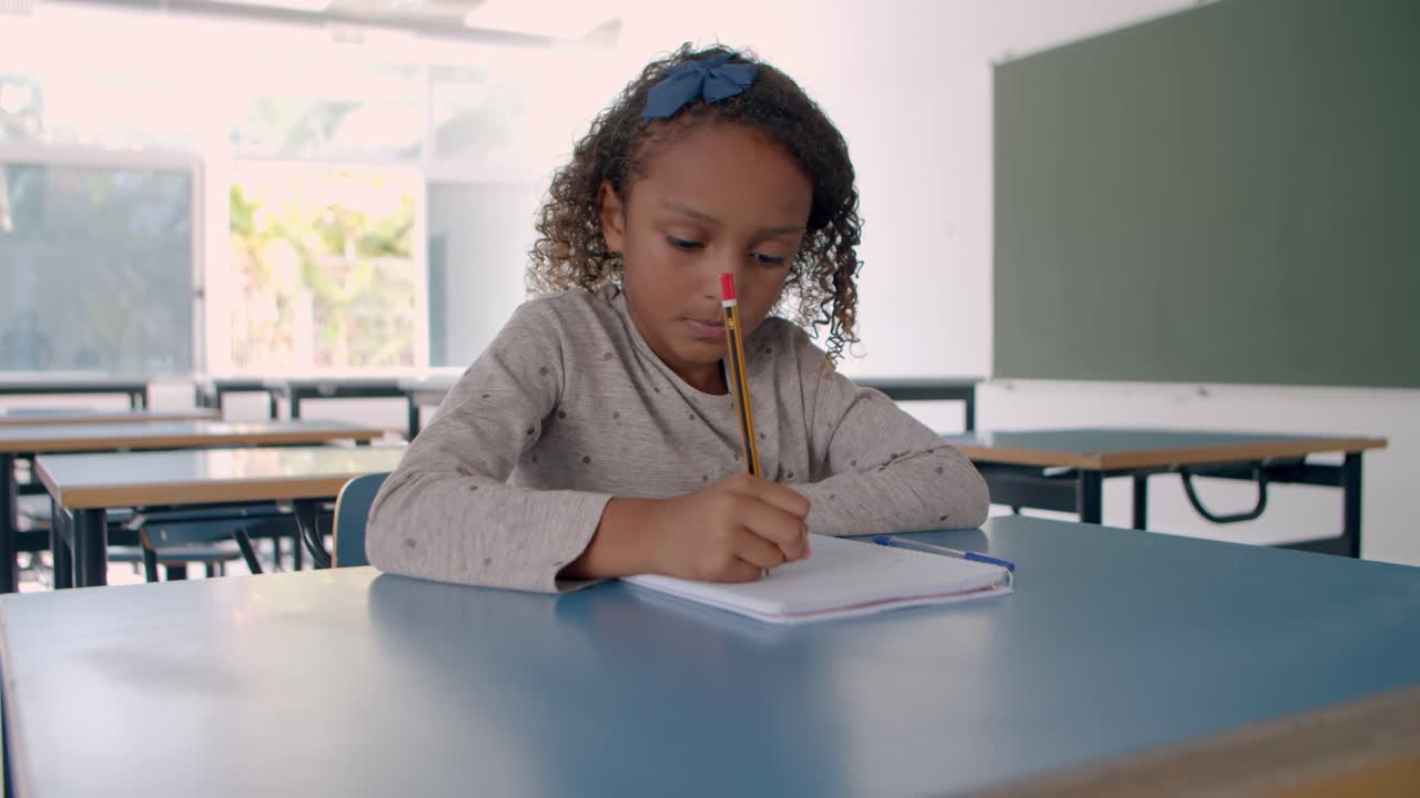 Free stock video - Young mixed girl writing on paper in classroom