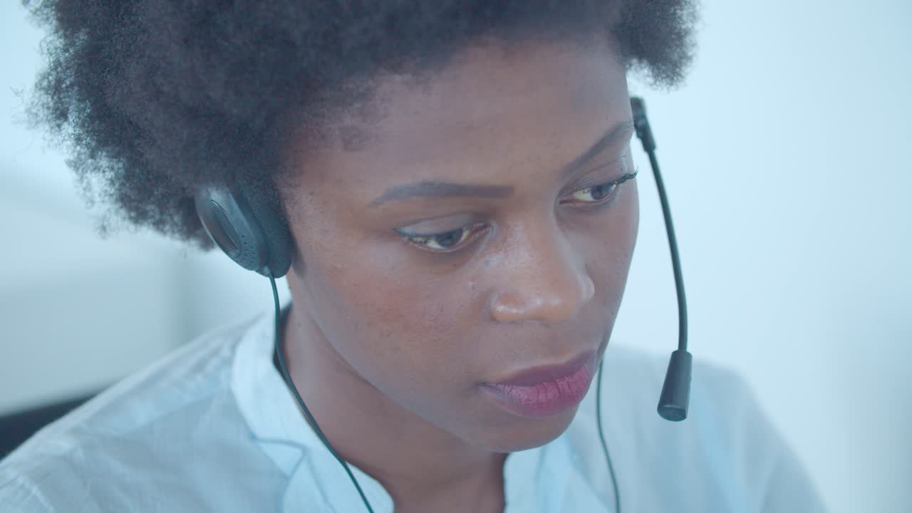 Free stock video - Focused african american employee in headset taking call