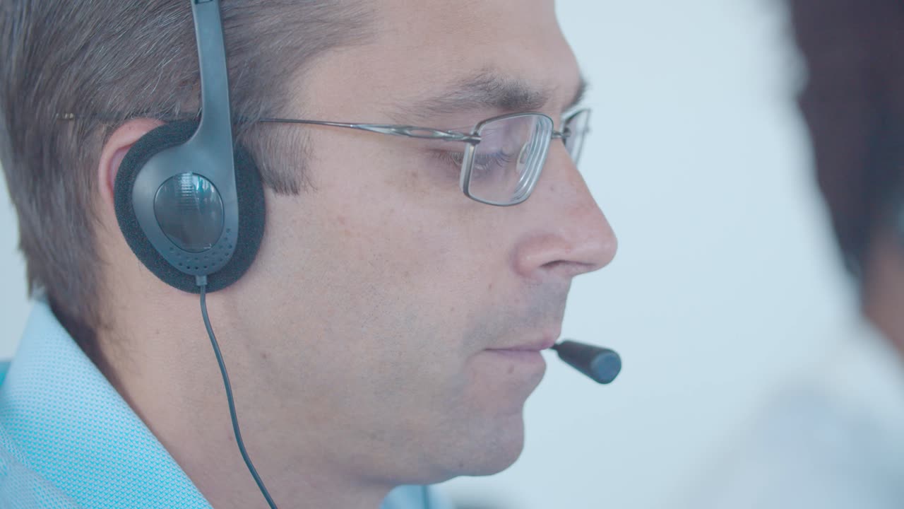 Free stock video - Focused male call center worker in headset taking call