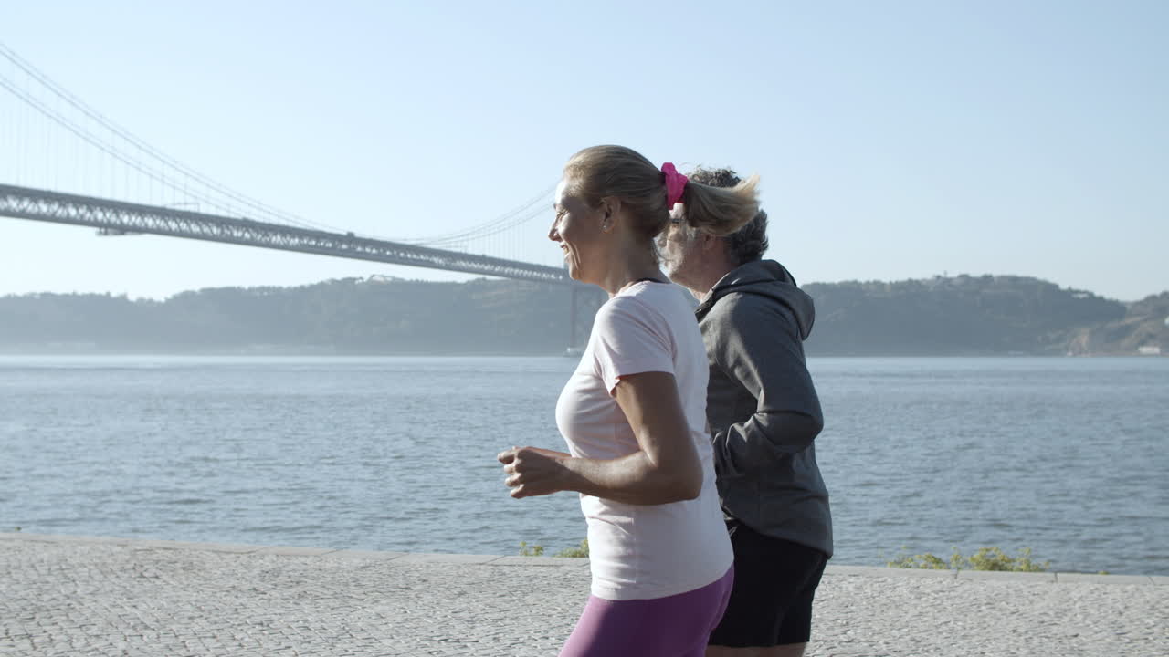 Free stock video - Caucasian couple jogging along sea, talking and smiling