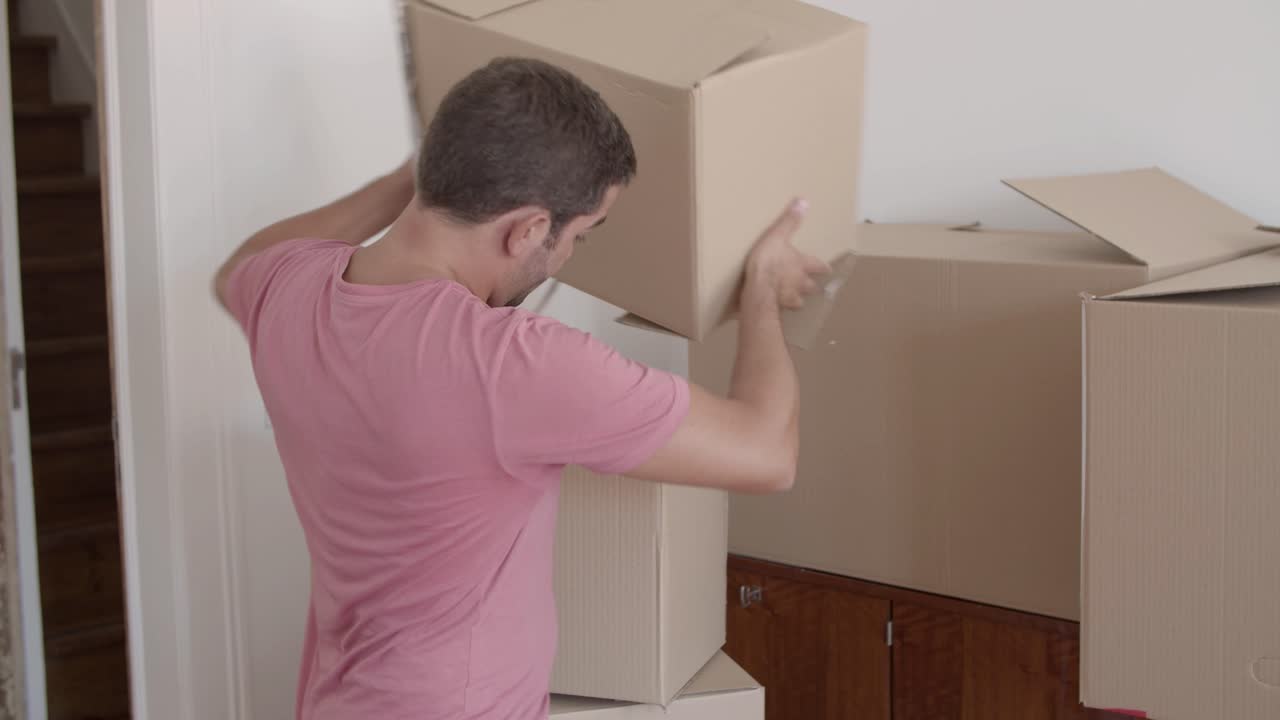 Free stock video - Handsome man putting two boxes on another one
