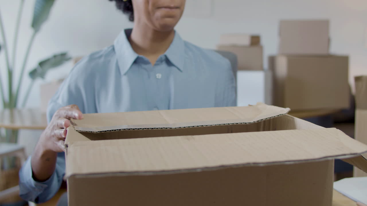 Free stock video - Female office worker packing goods in cardboard parcel