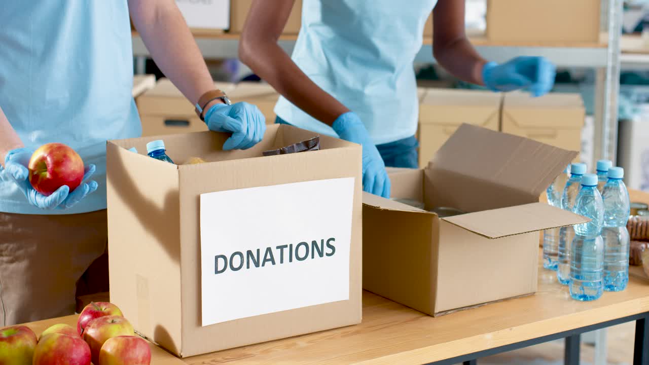 Free stock video - Close-up view of volunteers hands packing box with ...