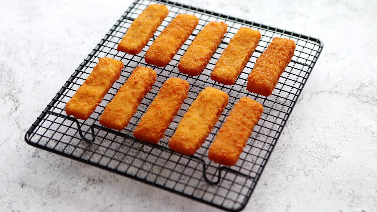 Premium stock video - Rows of golden fried fresh fish fingers fillets
