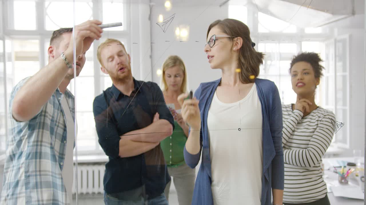 Premium stock video - Young people drawing on glass board