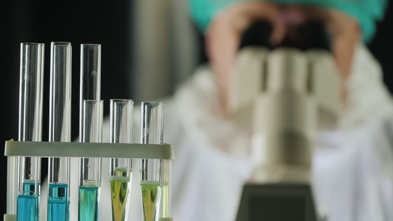 Vídeo de arquivo Premium - Tubos de ensaio no laboratório como um homem trabalha com um ...