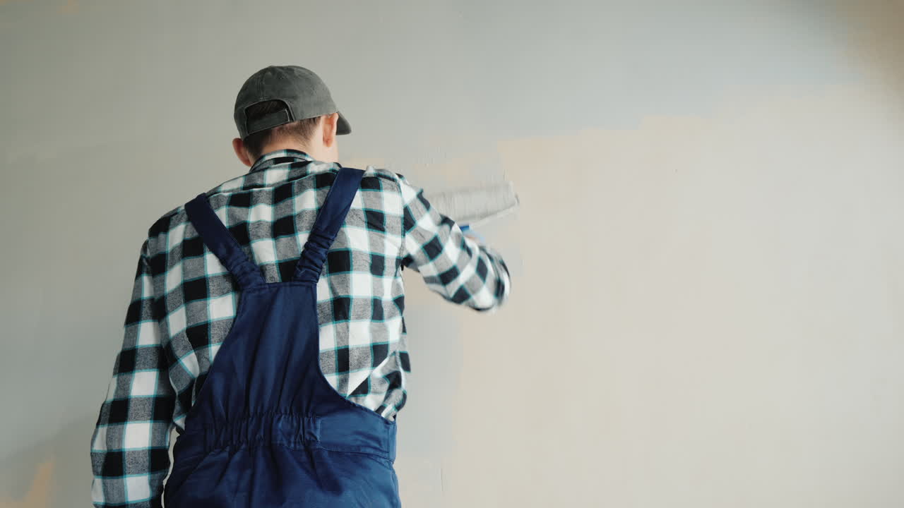 Premium stock video - Male builder paints wall with roller 1