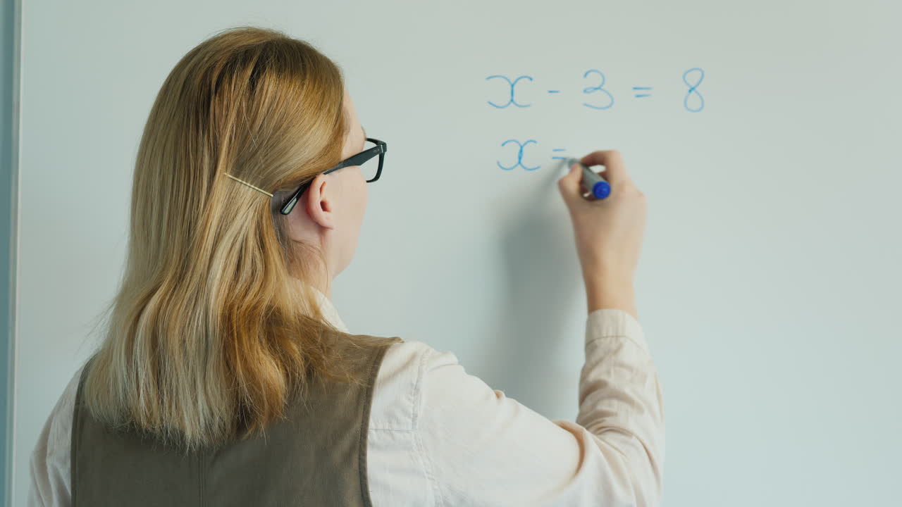 Premium stock video - Rear view of a teacher solving an equation in algebra