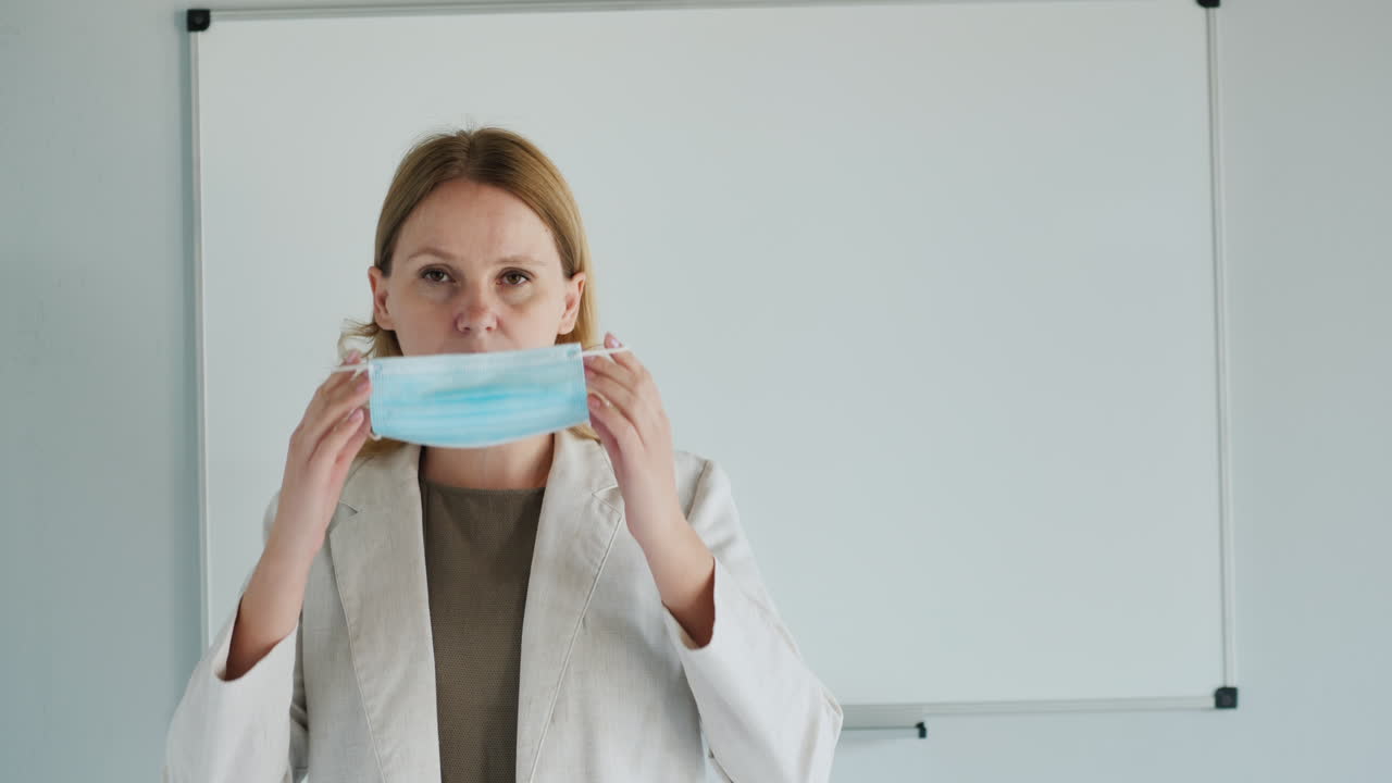 Premium stock video - Female teacher wears protective mask in front of ...