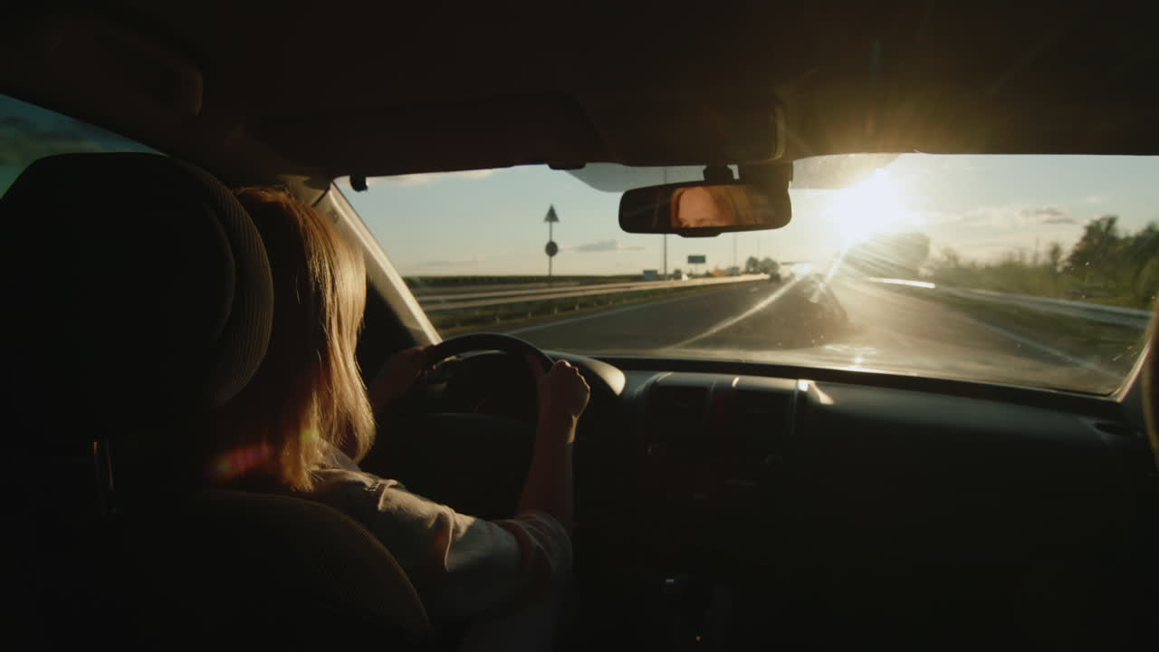 Premium stock video - Middle-aged female driver drives car in setting sun 2