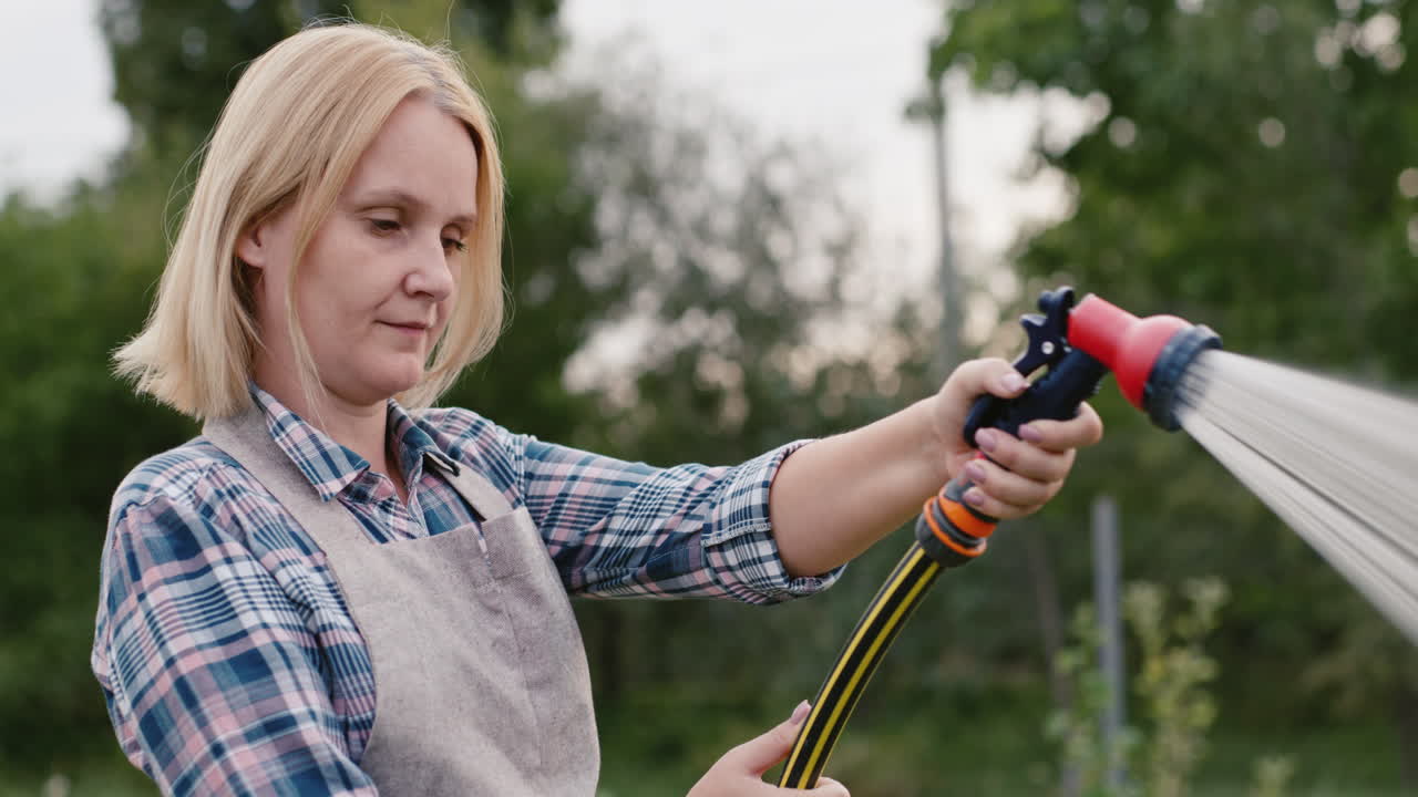 Premium stock video - A woman watering plants in her garden 1