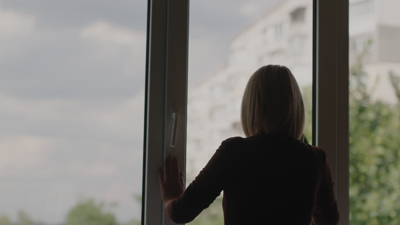 Premium stock video - A woman washes a window in the apartment of a ...