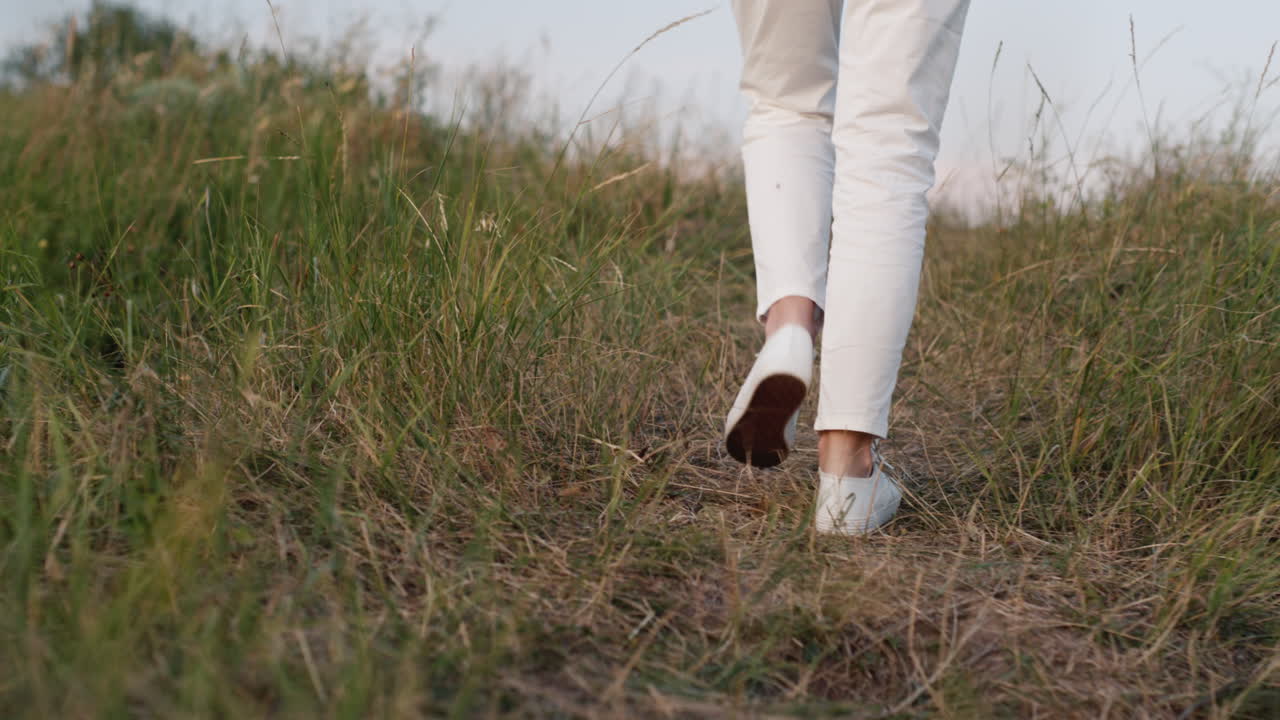 Premium stock video - The legs of a woman dressed in white clothes walk ...