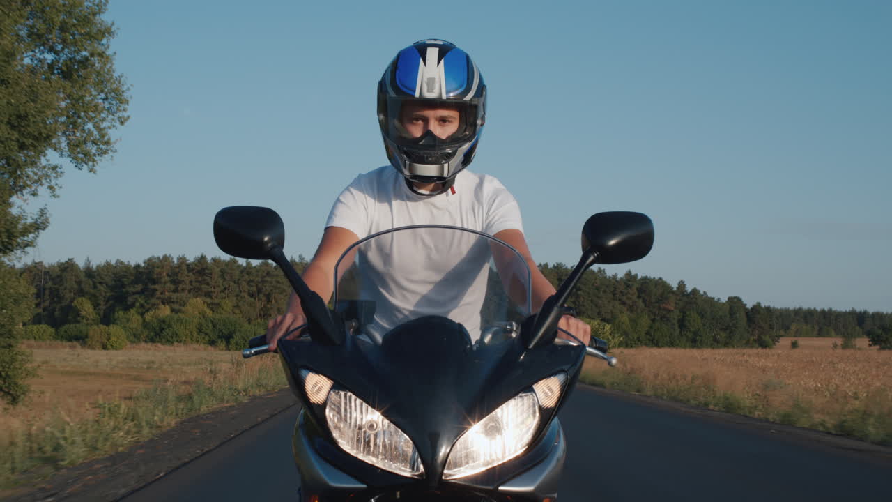 Premium stock video - Young man rides a motorcycle on the highway