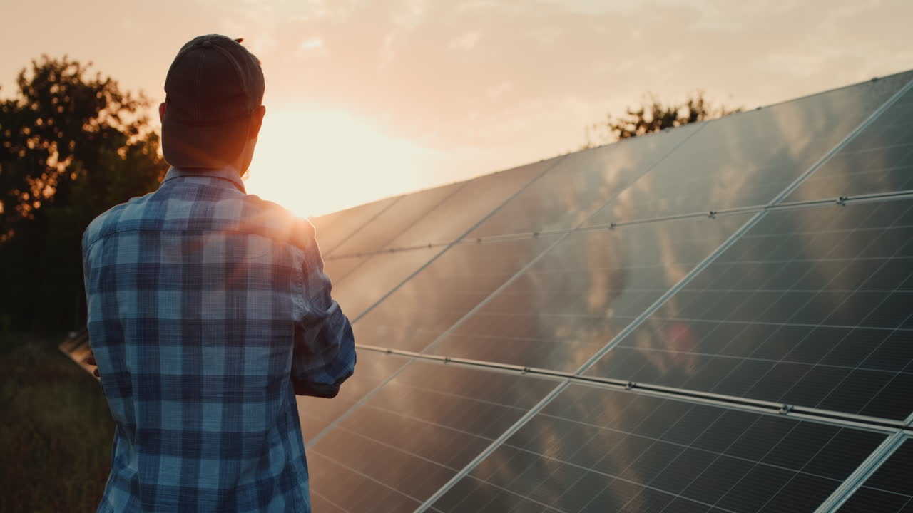 Premium stock video - Man looks at solar panels at sunset