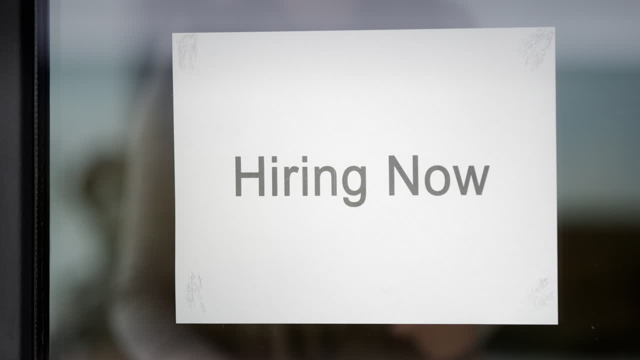Premium stock video - Worker removes and rips apart ad stating hiring now
