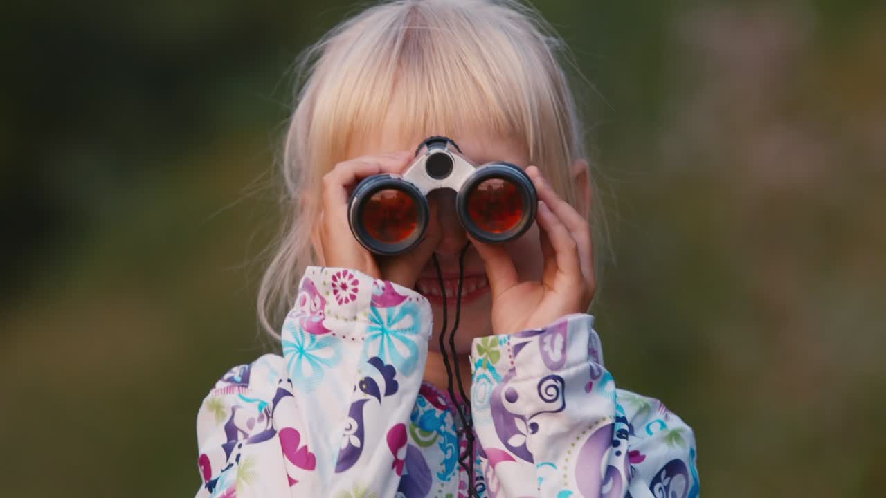 Vidéo de stock Premium - Un enfant joyeux regarde à travers des jumelles