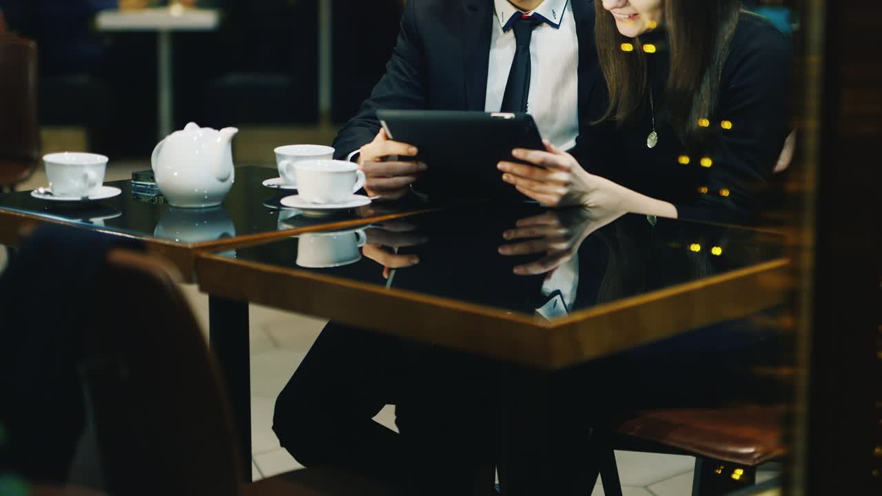 Premium stock video - A couple in love rests in a cafe and uses a tablet 2