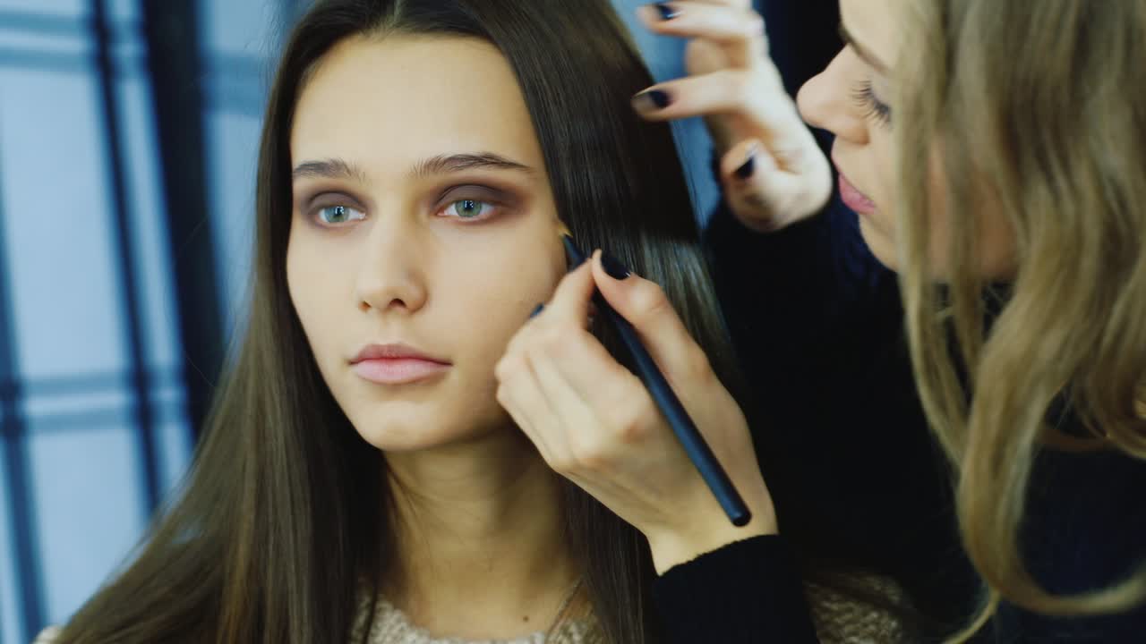 Premium stock video - Makeup artist young woman's make up in a studio 7