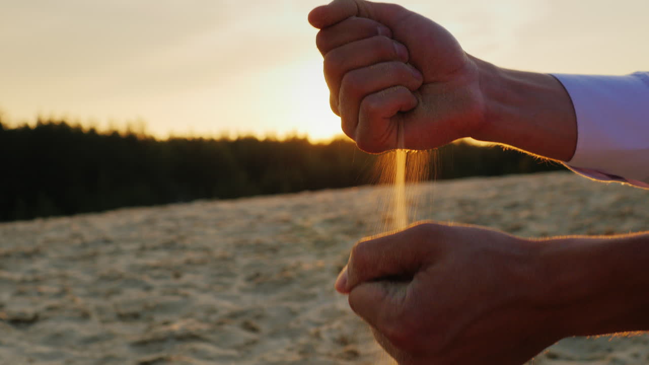 Premium stock video - Sands slip through the hands of man in a suit 1
