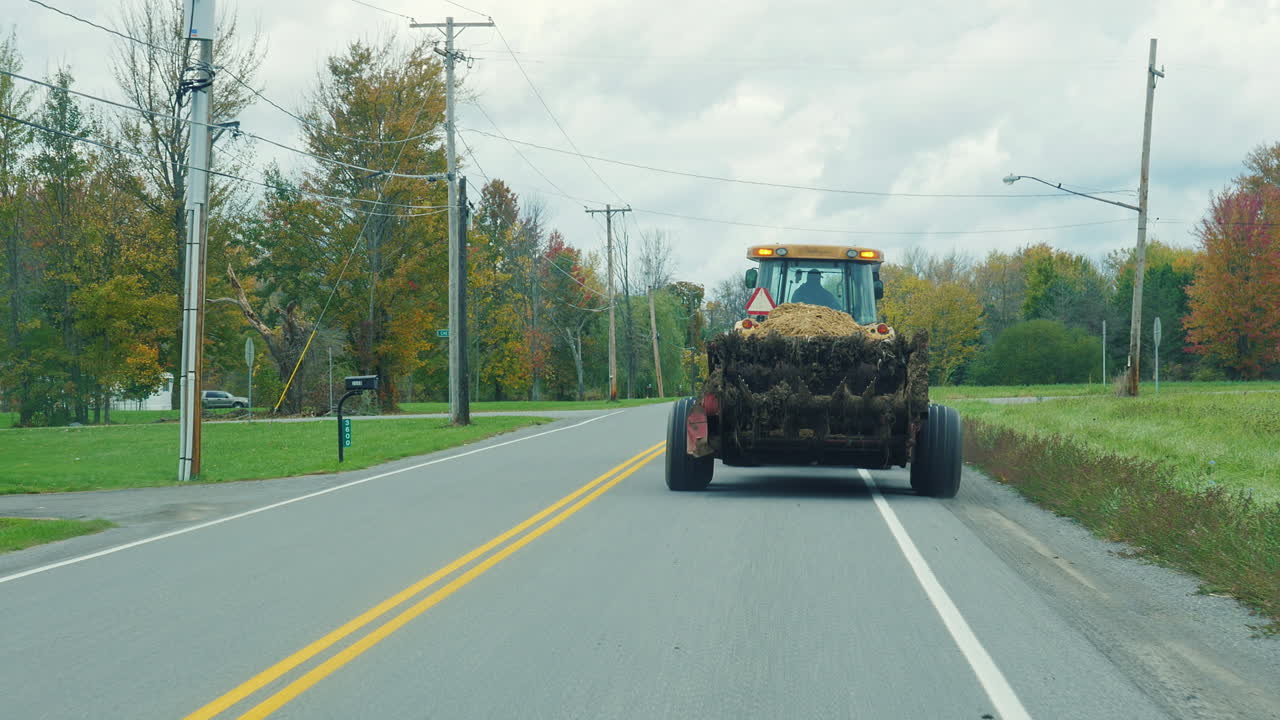 Premium stock video - A slow tractor rides on a typical american road ...