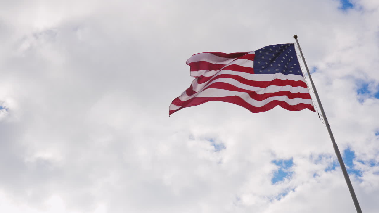 Premium stock video - Large us flag on a background of gray sky ...