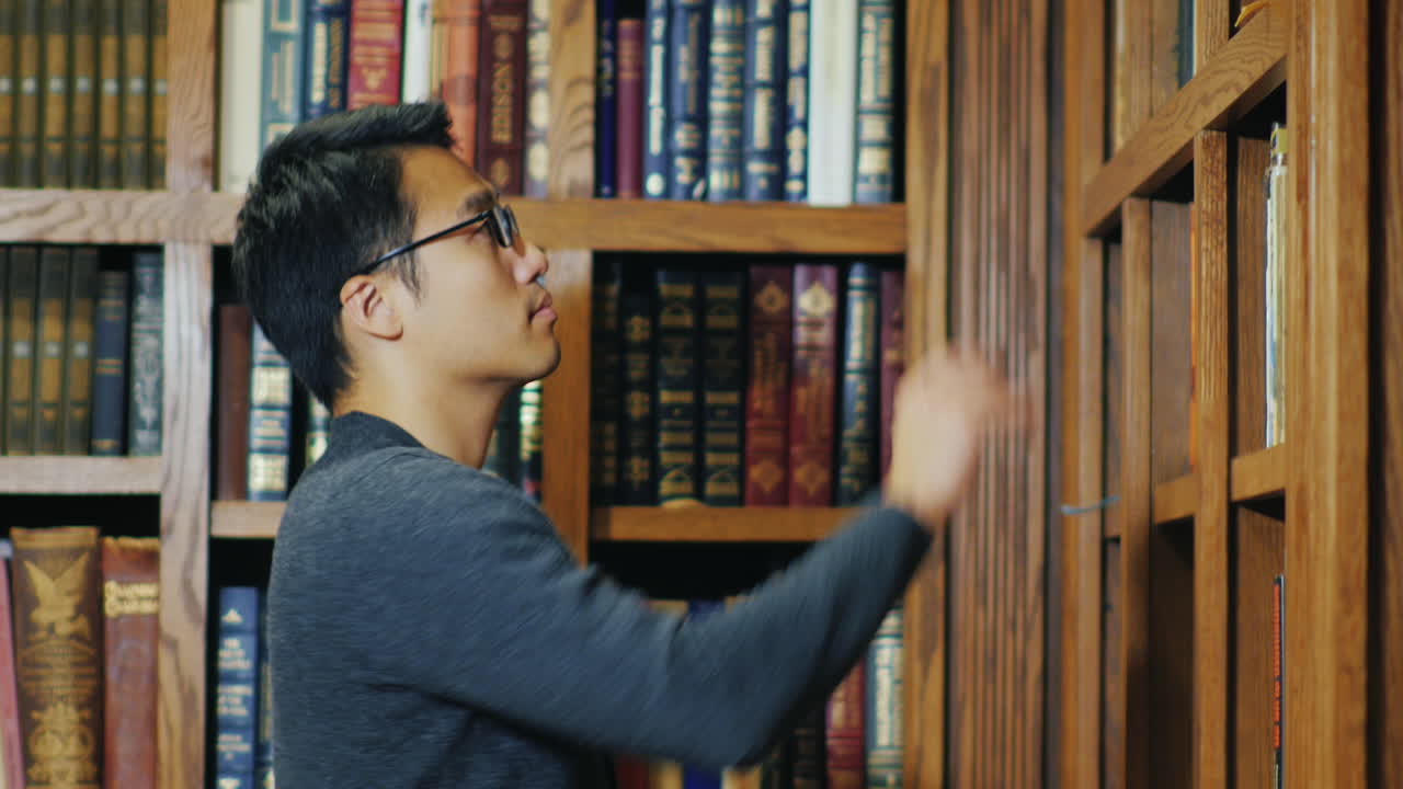 Premium stock video - Good looking asian man in glasses reading a book ...