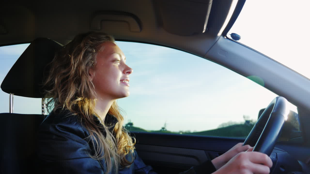 Premium stock video - Woman drives the car at sunset