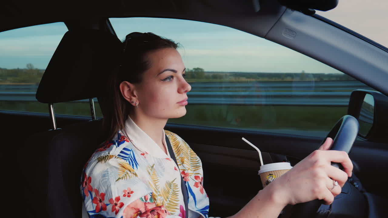 Premium stock video - A young woman is driving a car leisurely driving ...