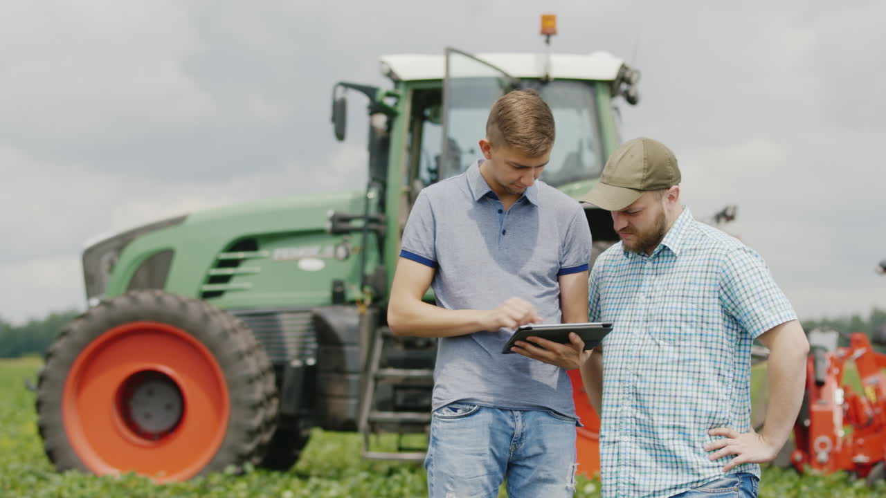 Premium stock video - Young farmers communicate in the field using a tablet